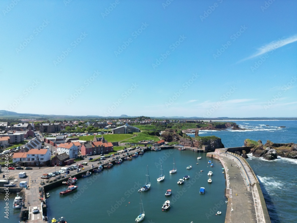 Aerial view of Dunbar harbour with boats docked and a clear blue sky ...