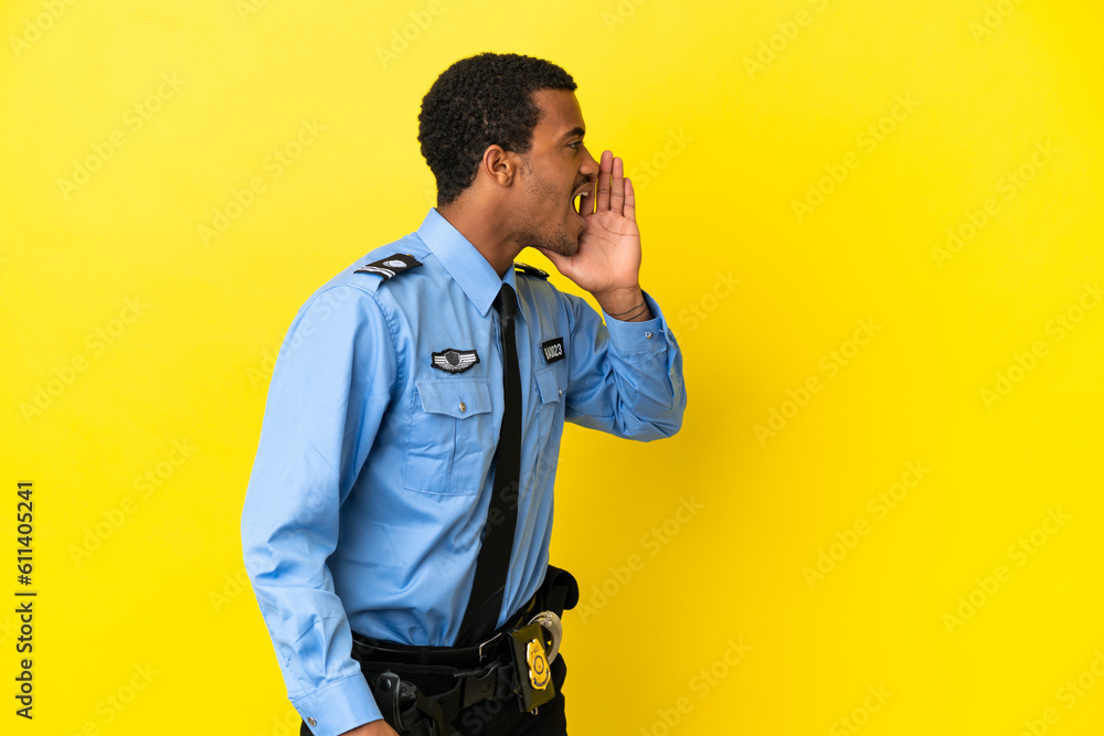African American police man over isolated yellow background shouting ...
