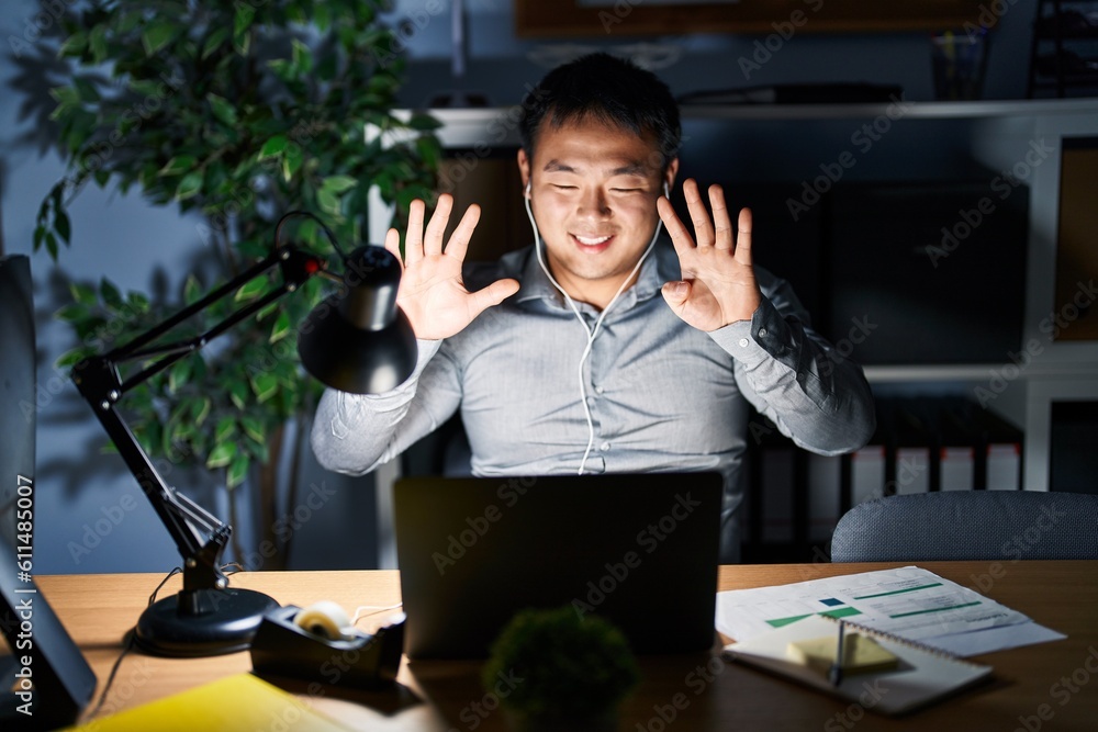 Young chinese man working using computer laptop at night showing and ...