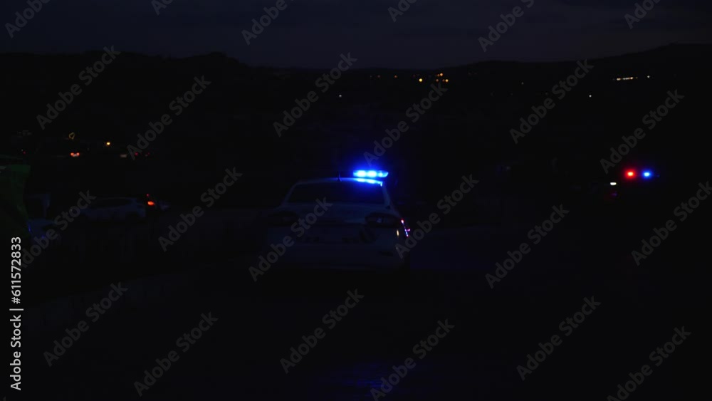 Flashing police car lights during a night shift. A police officer walks ...