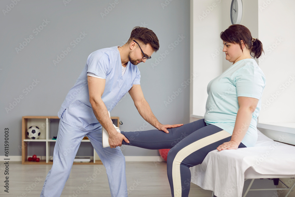 Physiotherapist examines an overweight female patient. Side view of a ...