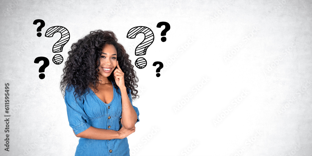 African woman with smiling look, question marks on empty grey wall ...