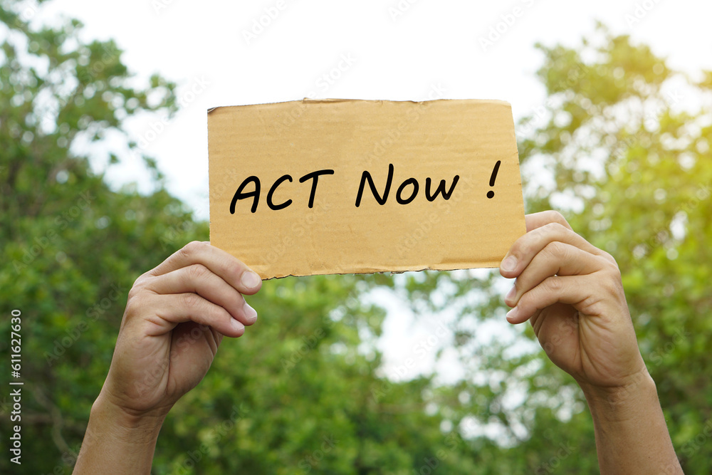 Hands hold paper sign with text Act Now!. Concept , protest, calling ...