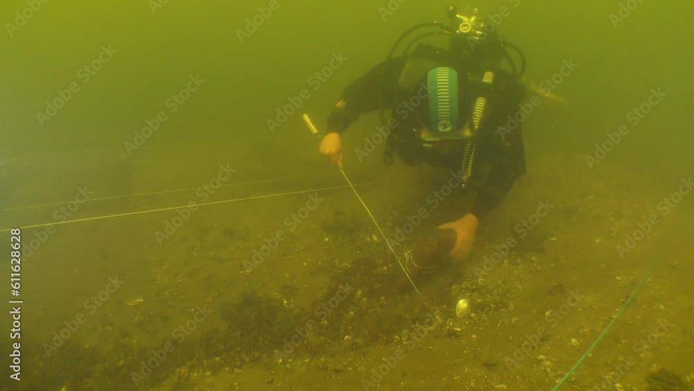Underwater archaeological research: a scientist diver, using a metal ...