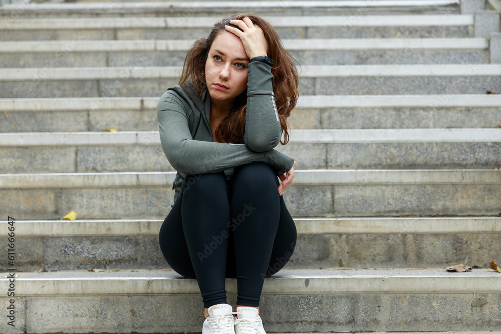 Disappointed and sad woman sitting on stairs. She sits alone and thinks ...