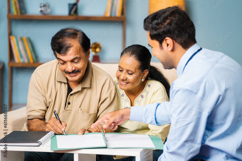 Indian banker taking signature from senior man while with wife at home ...