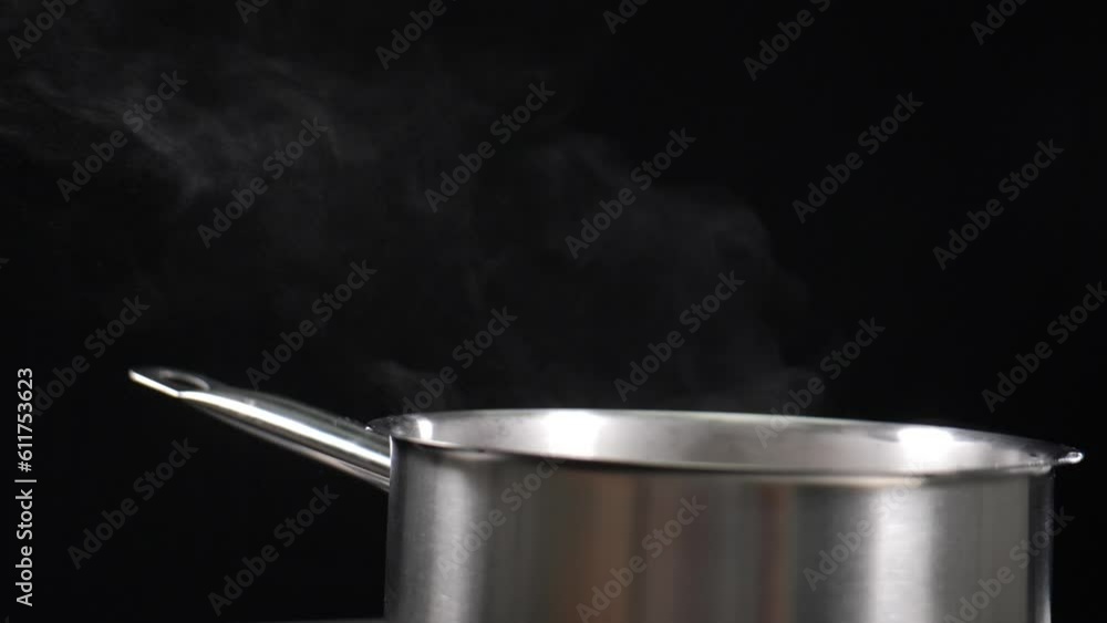 Large Saucepan with long handle on black background. Steam and white ...