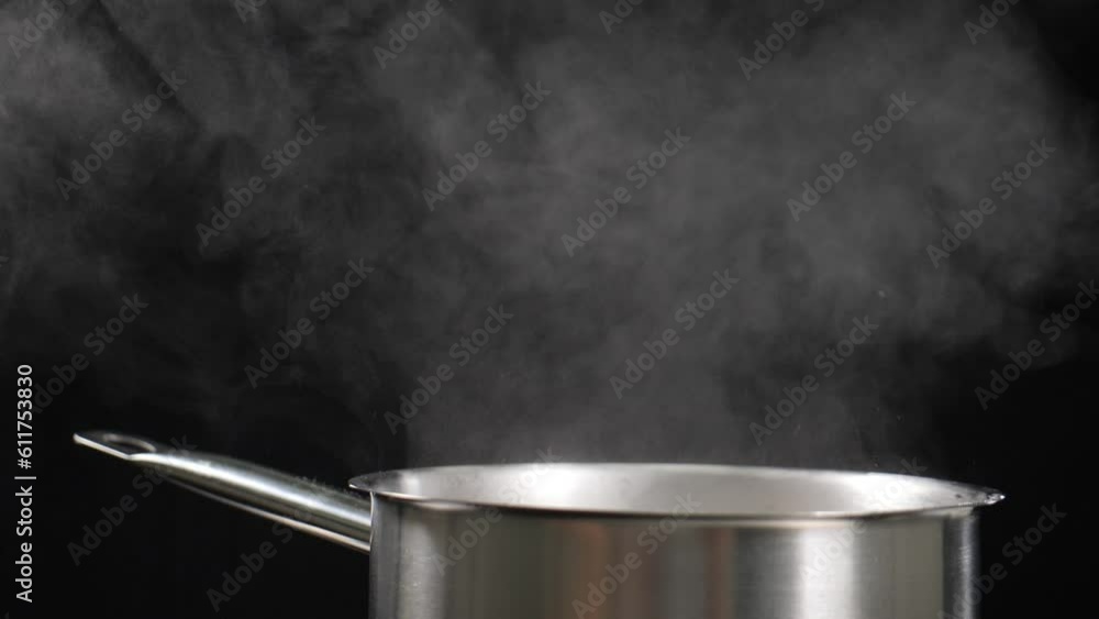 Large Saucepan with long handle on black background. Steam and white ...