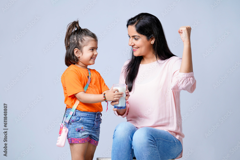 Indian mother giving milk in glass his daughter on white background. Stock Photo | Adobe Stock