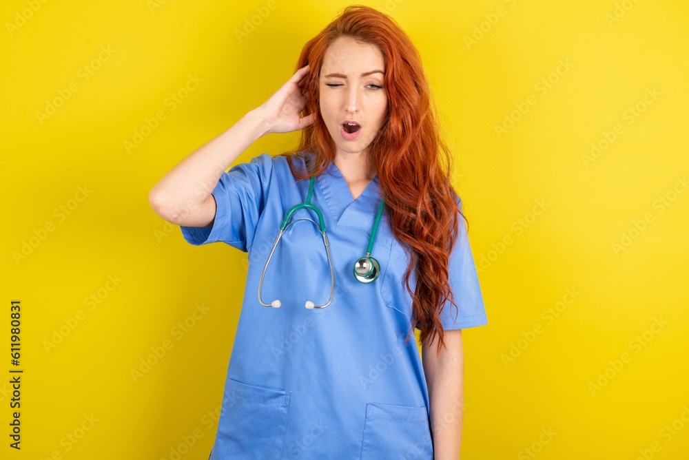 young red-haired doctor woman over yellow studio background yawns with ...