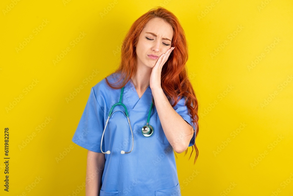 young red-haired doctor woman over yellow studio background with ...