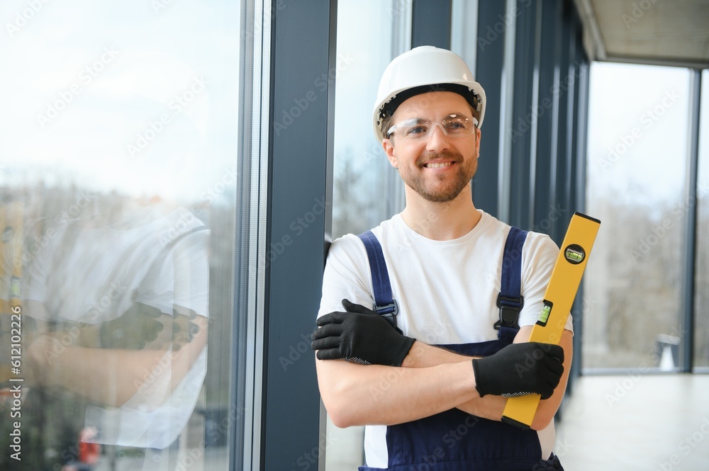 handsome young man installing bay window in new house construction site ...