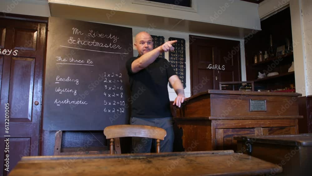 Wide shot of a male teaching in old victorian school classroom. The ...