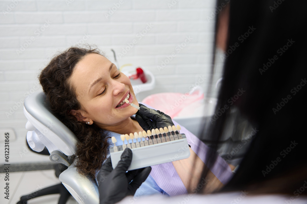 Dentist doctor placing tooth color chart, over a beautiful smiling ...