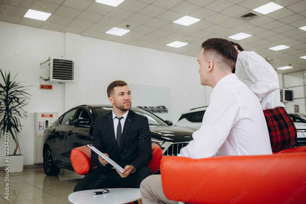 Mid-adult couple talking with sales agent and signing contract for new ...