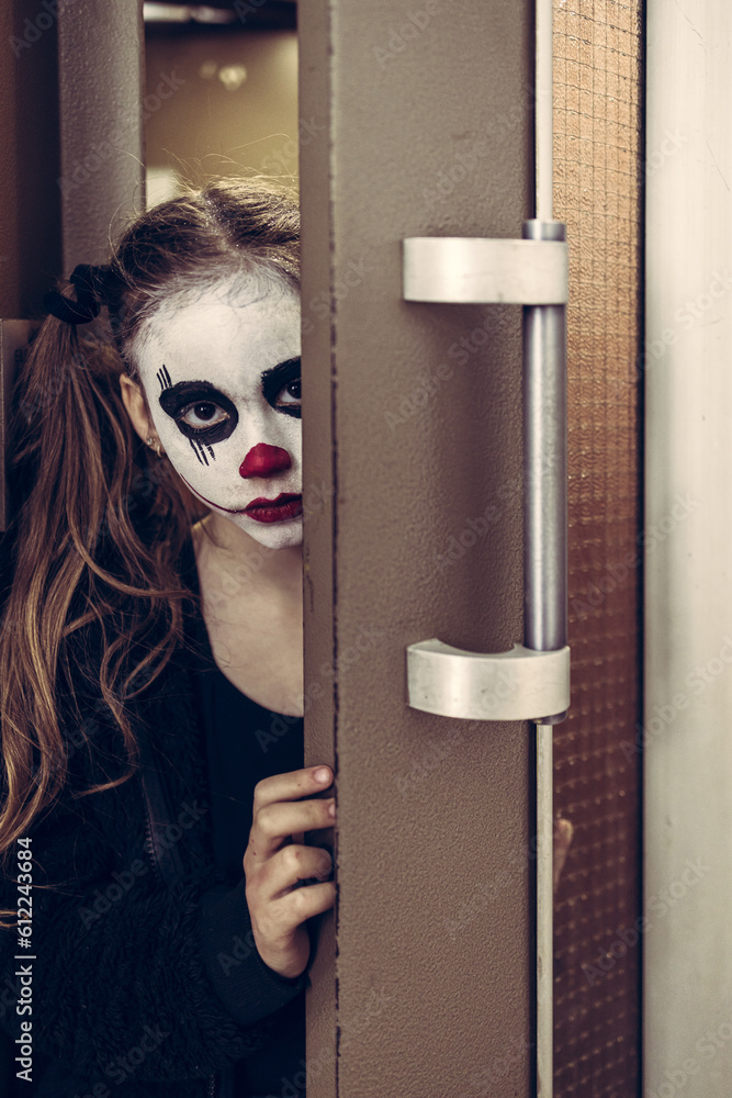 A 9-year-old girl with makeup like a scary clown emerges from the elevator. Black and white ...