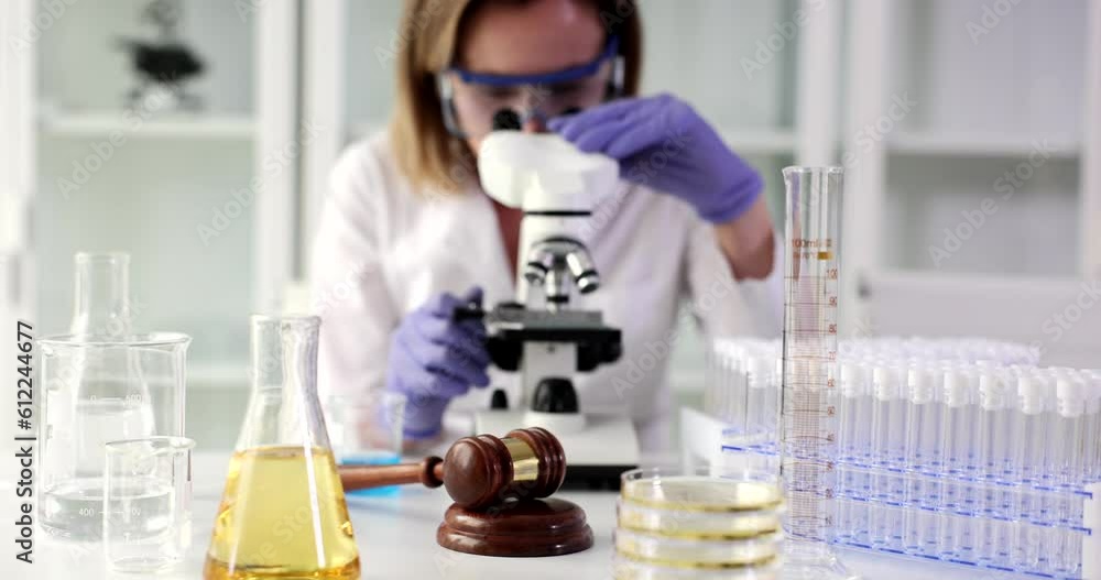 Medical examiner looks through a microscope and examines evidence from ...