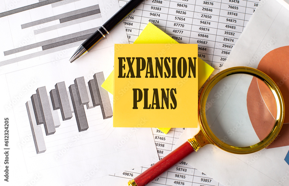 EXPANSION PLANS text on a sticky on the graph background with pen and ...
