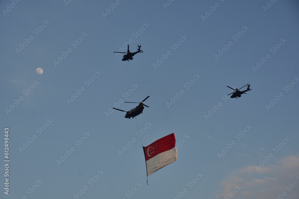 Helicopters flying in the blue sky while holding the Singapore flag ...