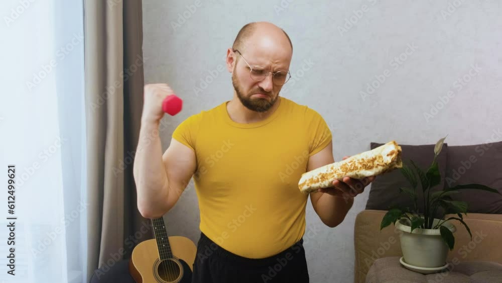 Muscular man trains and looks sad at calorie food. Diet and willpower ...