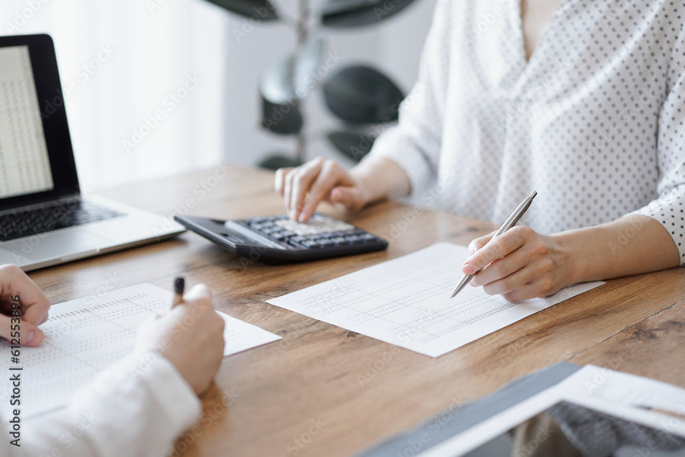 Woman accountant using a calculator and laptop computer while counting ...