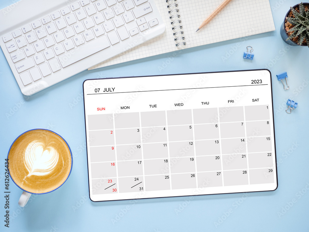 Top view, tablet computer showing July 2023 calendar app page and ...