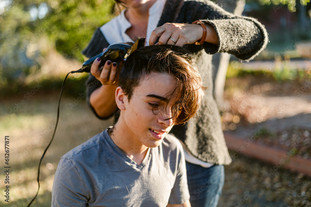 Teen boy getting buzz haircut By mother outdoors Stock Photo | Adobe Stock