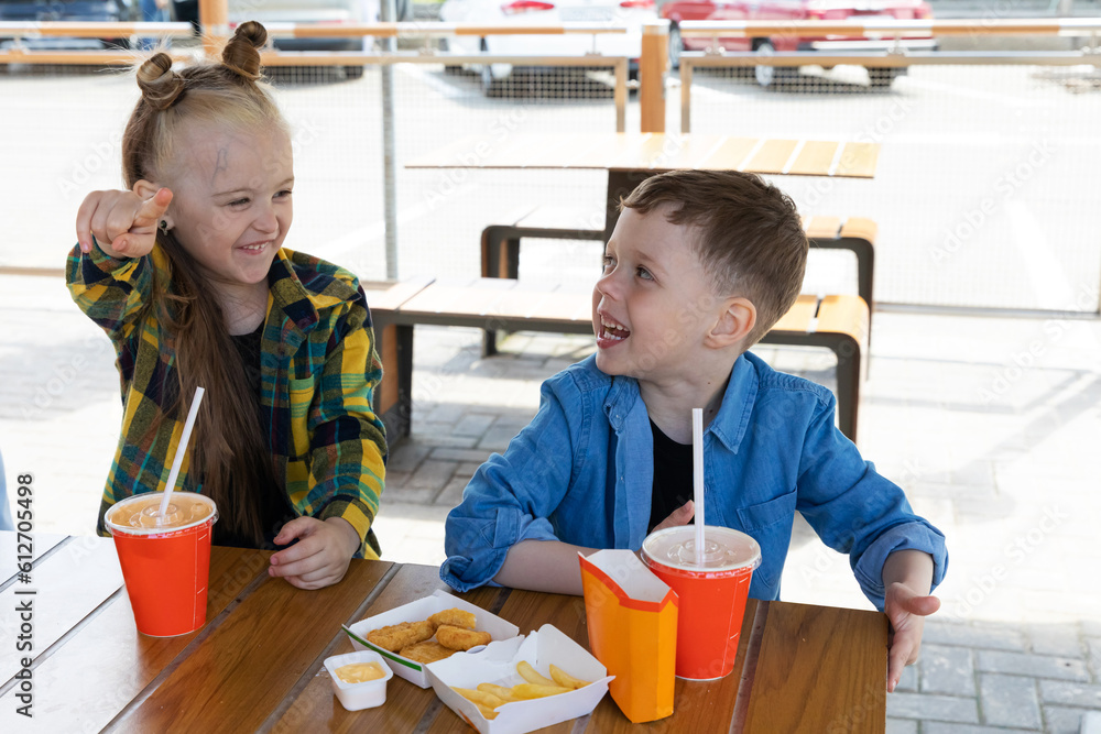 Happy children girl and boy brother and sister eat nuggets and french ...