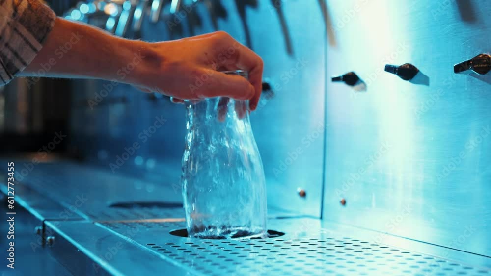 Male hand of bartender washing glass with rinser and pouring fresh ...
