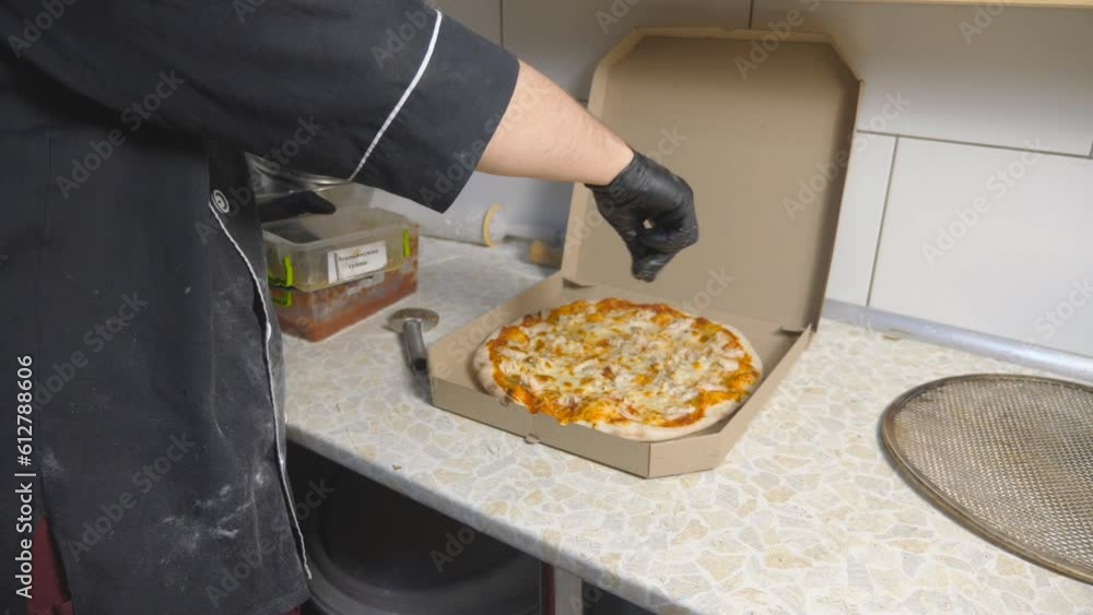 Male chef strewing of dried herbs a tasty baked dish in a carton box at ...
