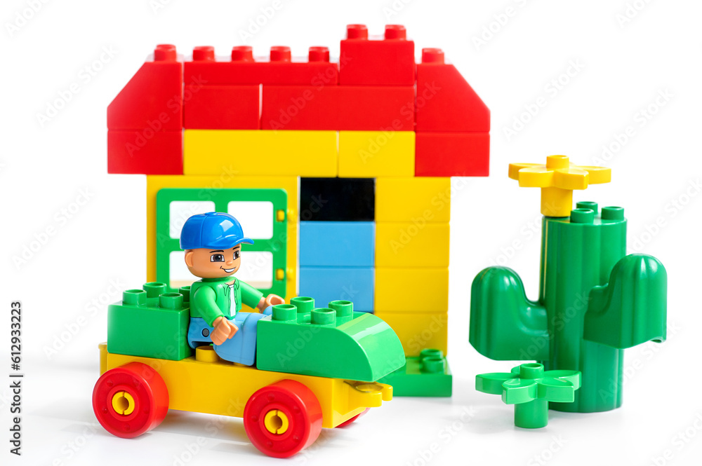 Lego man in a car on the background of a house made of colorful blocks ...