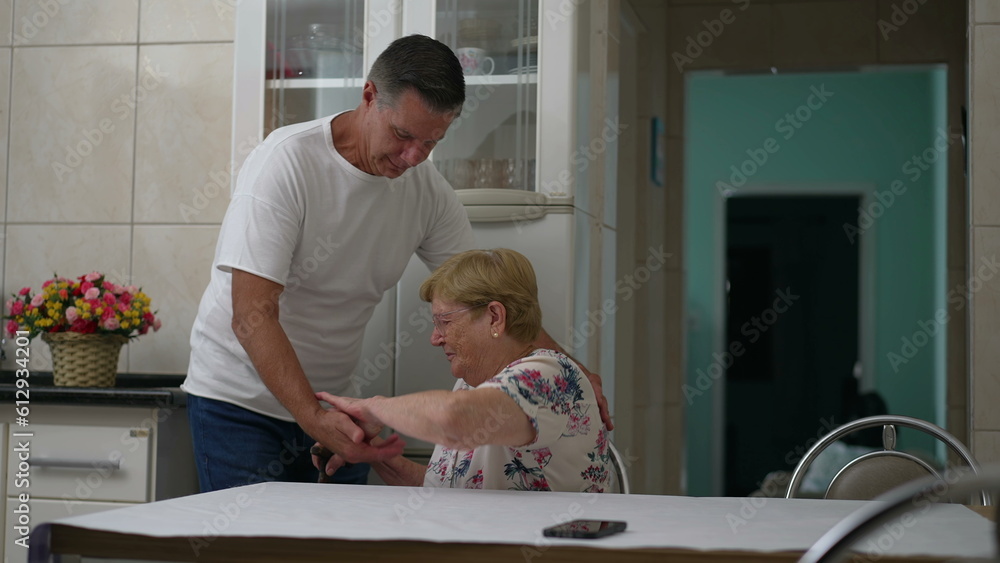 Caretaking moment of middle-aged son helping elderly mother get up from ...