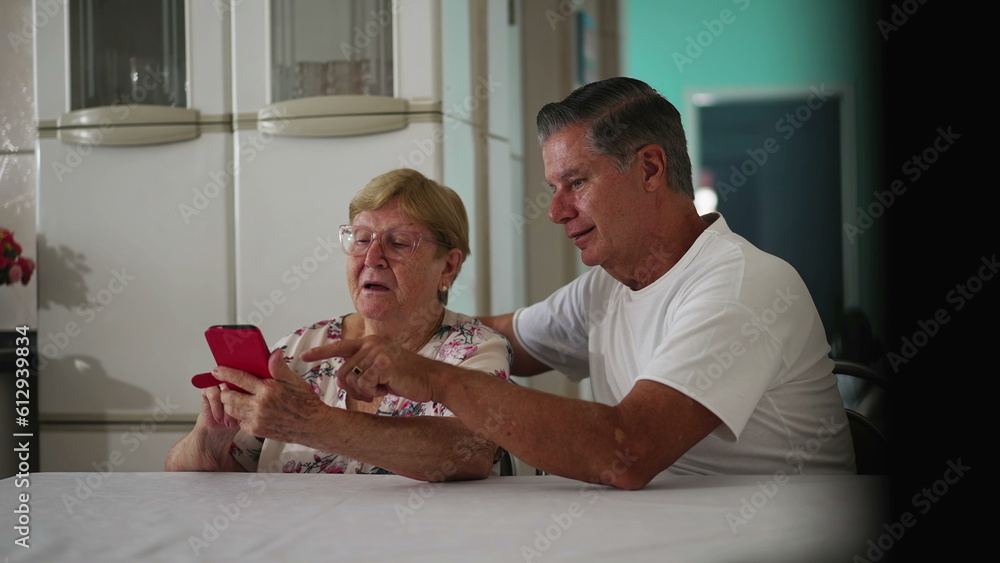 Candid Middle-Aged son helping elderly mother with modern technology in ...