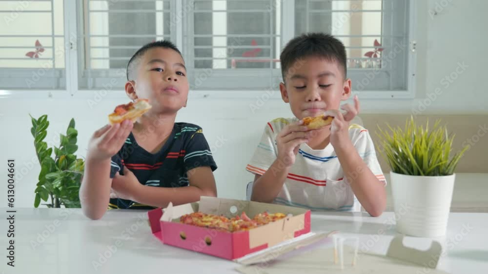 Happy Asian two little boy 5 years sitting eating huge pizza together ...