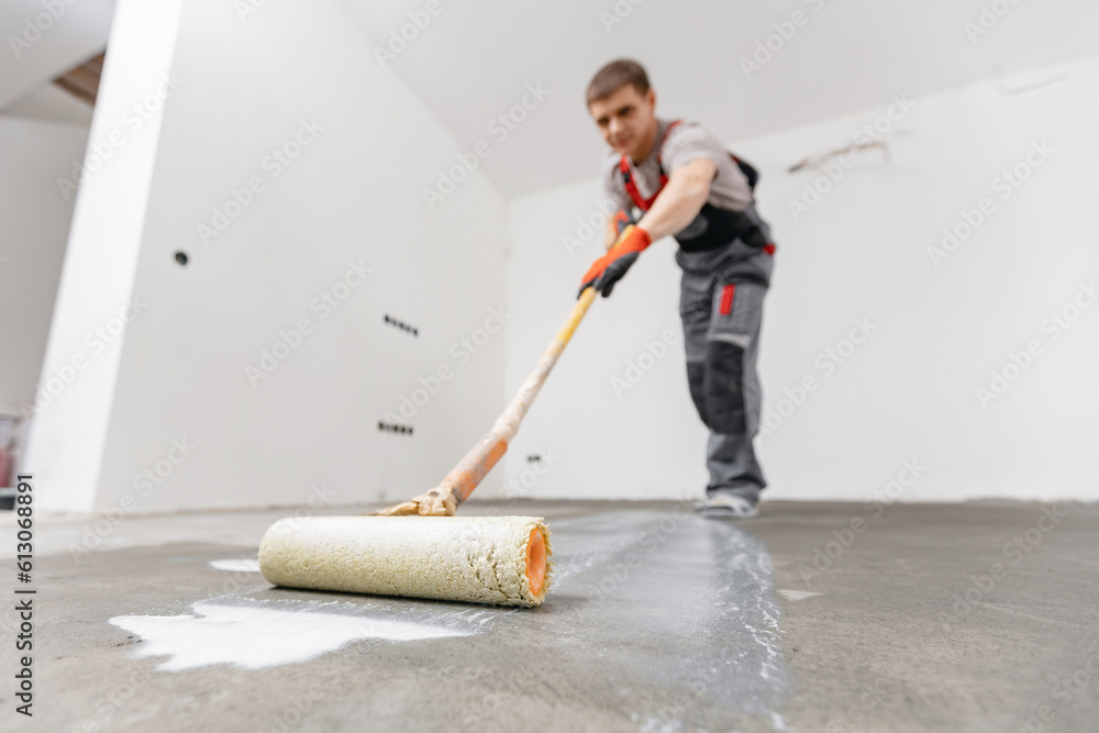 Floor priming process. Worker use primer on concrete floor before ...
