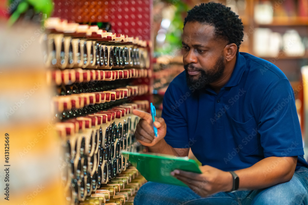 African man liquor shop worker working and counting a bottle of wine ...