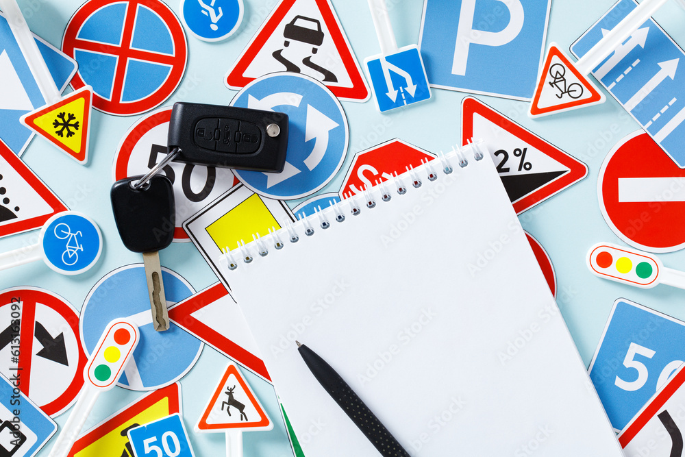 Driving school test concept. Blank paper notebook, car keys, road signs ...