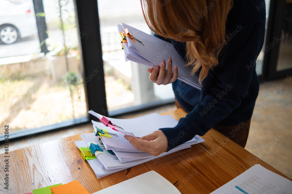 secretary searches through stacked documents on desk in office to find ...