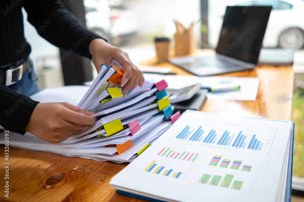 secretary searches through stacked documents on desk in office to find ...