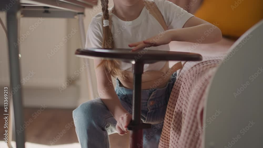 Little girl with back supporting braces plays with classic piano stool ...