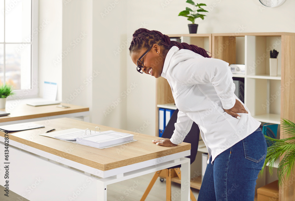 Young black woman feels back pain after sedentary work, sitting at home ...