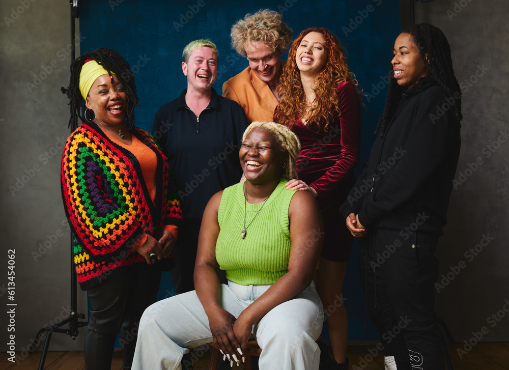Portrait of six LGBTQIA queer people laughing against studio backdrop ...