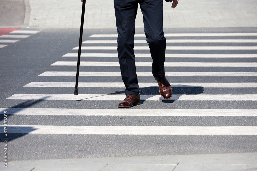 Man in trousers walking with a cane on crosswalk. Male legs on ...