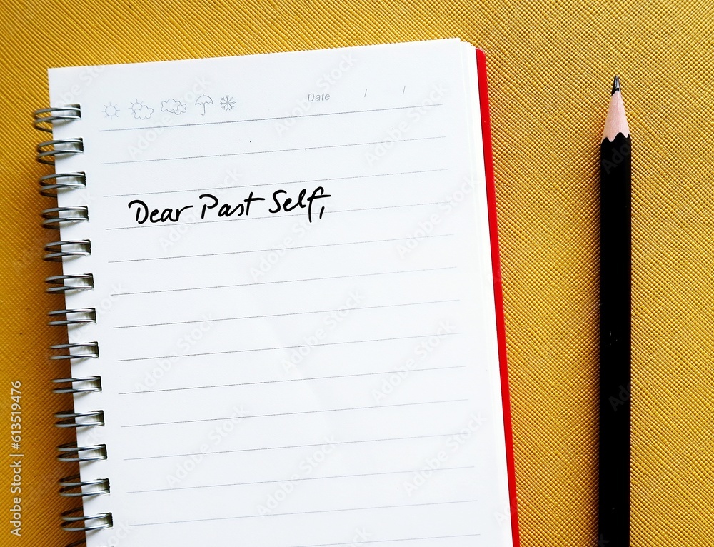 Notebook on yellow background with handwritten text DEAR PAST SELF ...
