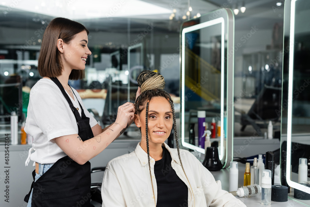 salon experience, happy hair stylist doing hair bun to female client ...