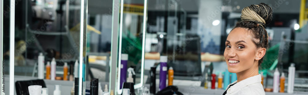 cheerful client in beauty salon, happy woman with hair bun looking at ...