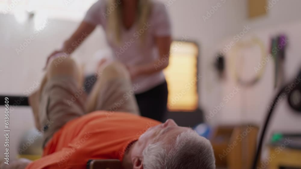 Senior man exercising in Pilates machine guided by a female Pilates ...
