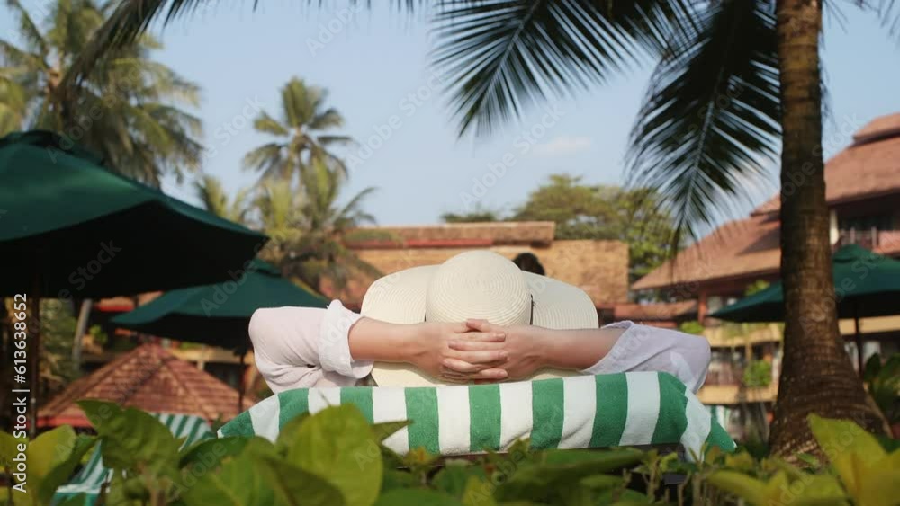 Woman tanning sunbathing lying in sunbed in hotel park area putting ...