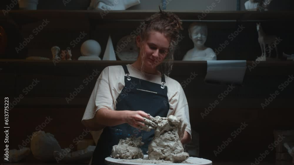 A talented sculptor girl creates a sculpture of a fat woman from clay ...