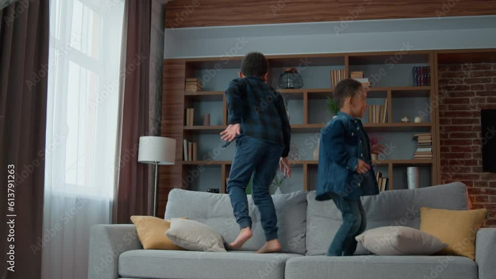 Two little kids boys jumping together on couch at living room. Funny ...